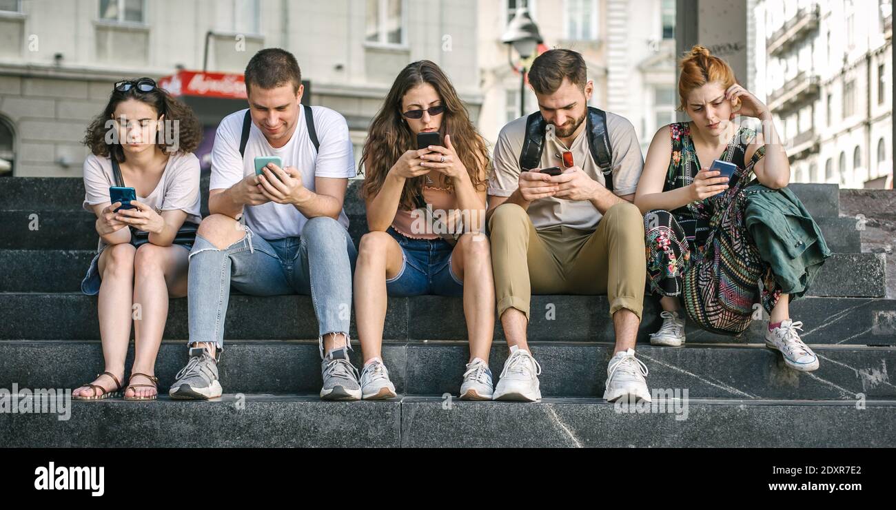 Group of friends using smartphones together. Young people addiction to ...