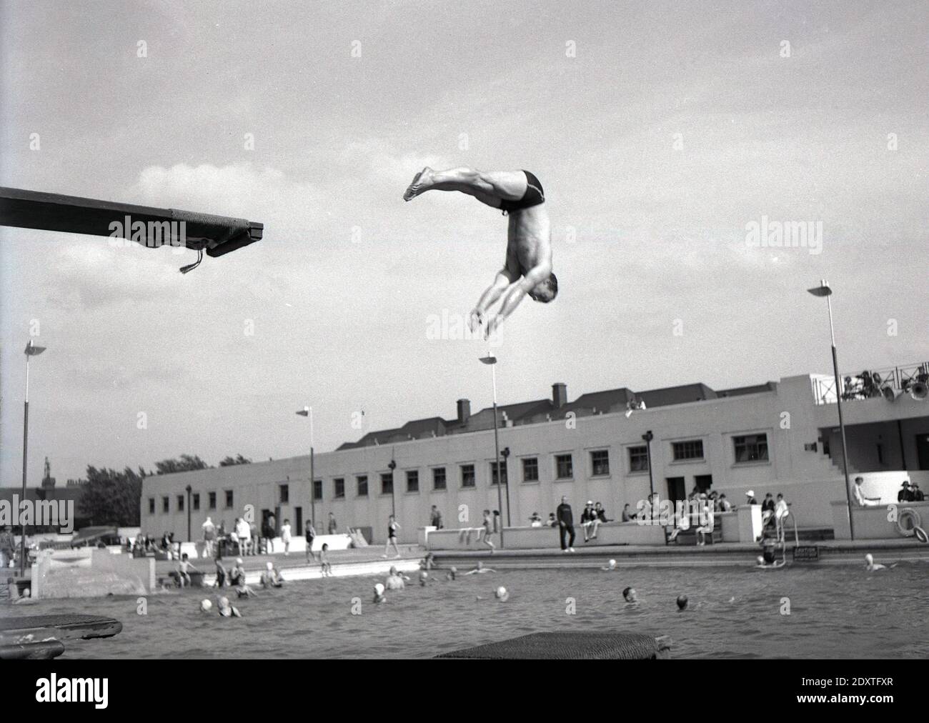 1950s, historical, open air Lido, a man doing a forward dive from a ...