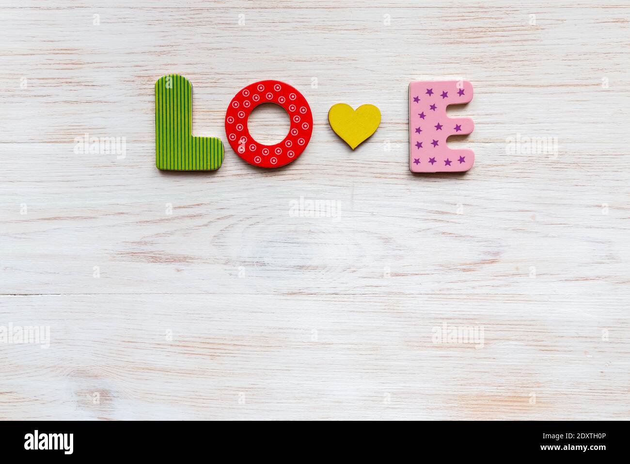 Colorful wooden letters and heart forming word LOVE written on white ...