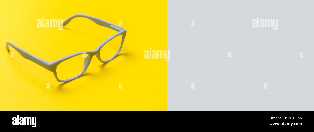 Grey glasses on a yellow and grey background. Top view, space for your ...