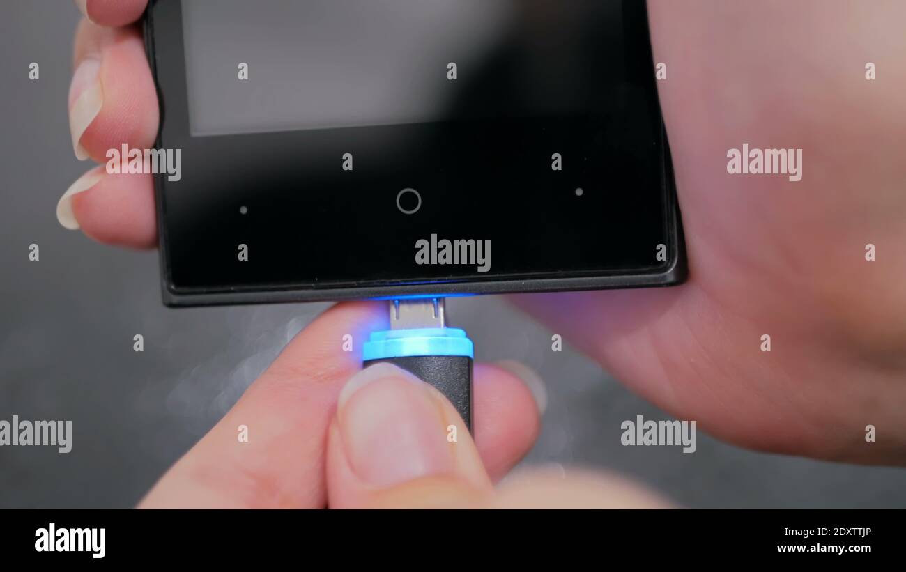 Woman's hand plugging black lightning charging cable into smartphone ...
