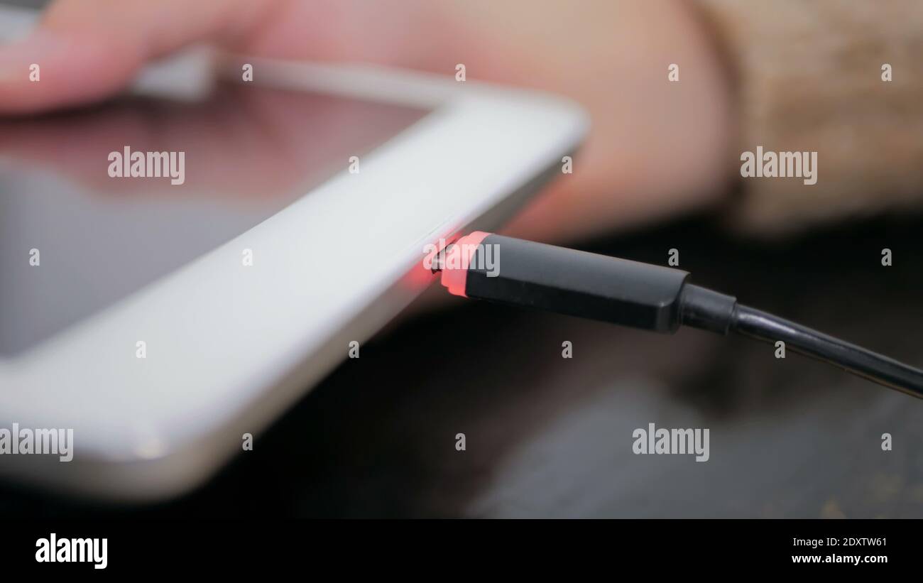 Woman's hand plugging black lightning charging cable into tablet Stock ...