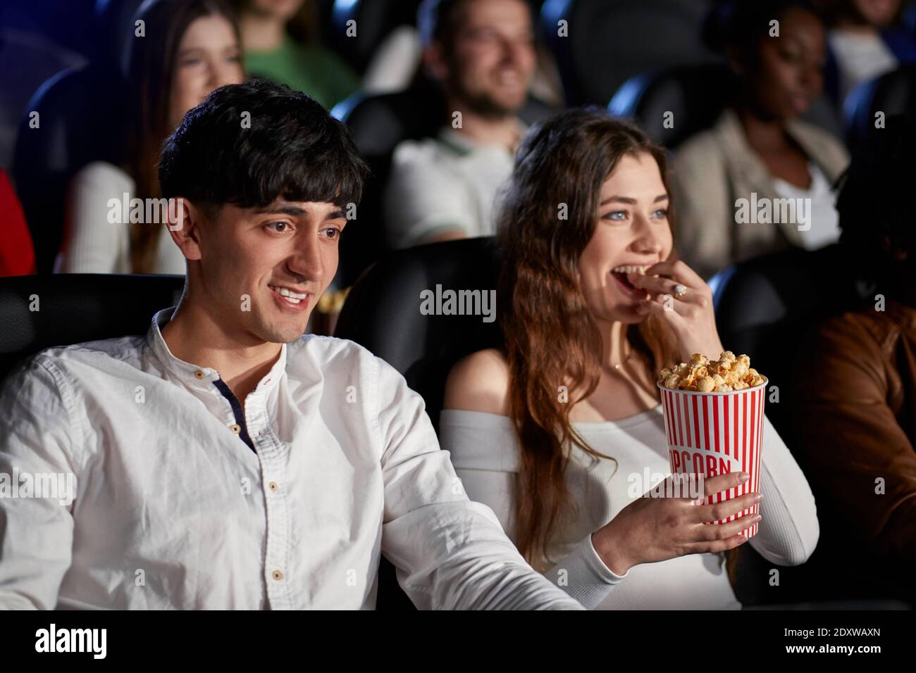 Selective focus of young man laughing, eating popcorn while watching ...