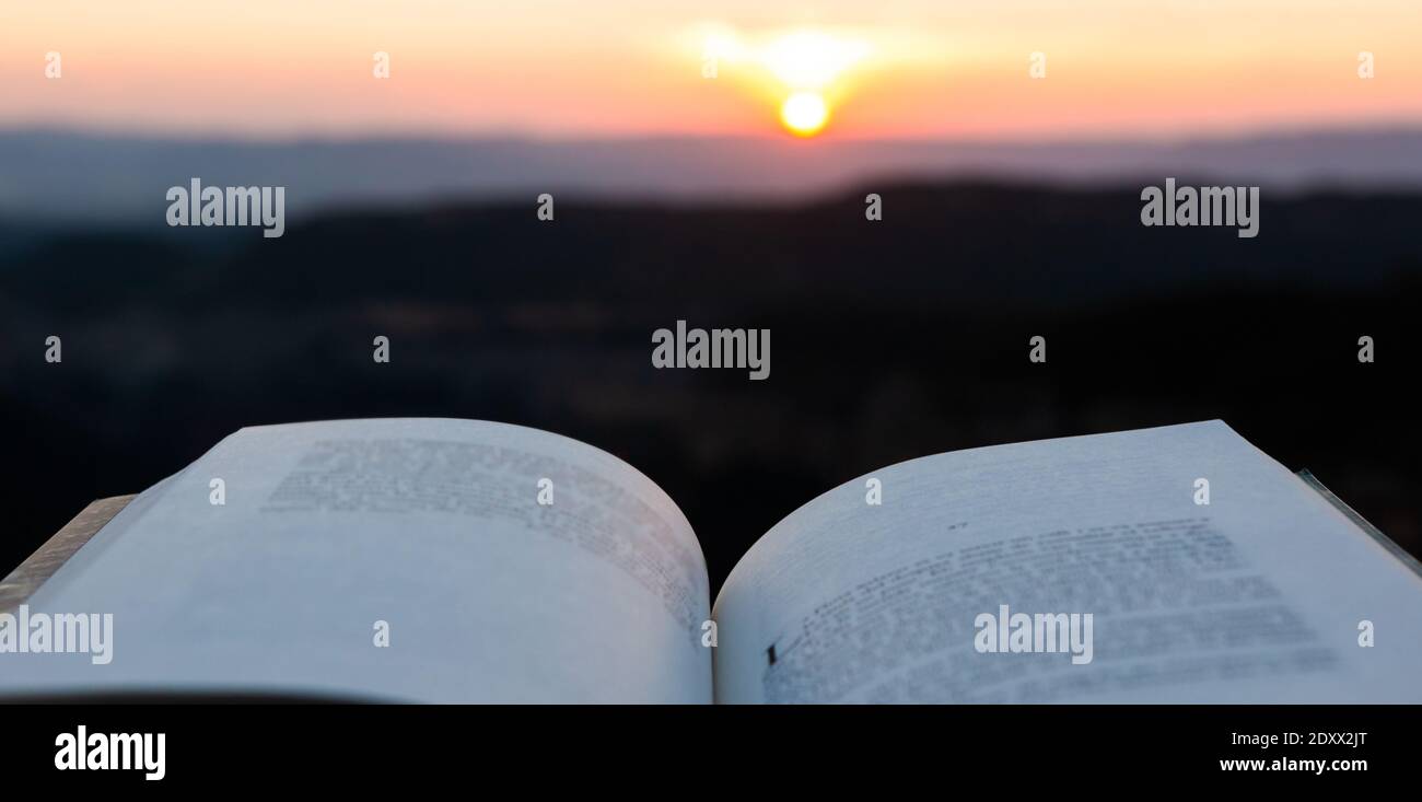 Open book with sunset or sunrise in the background. Open book with ...