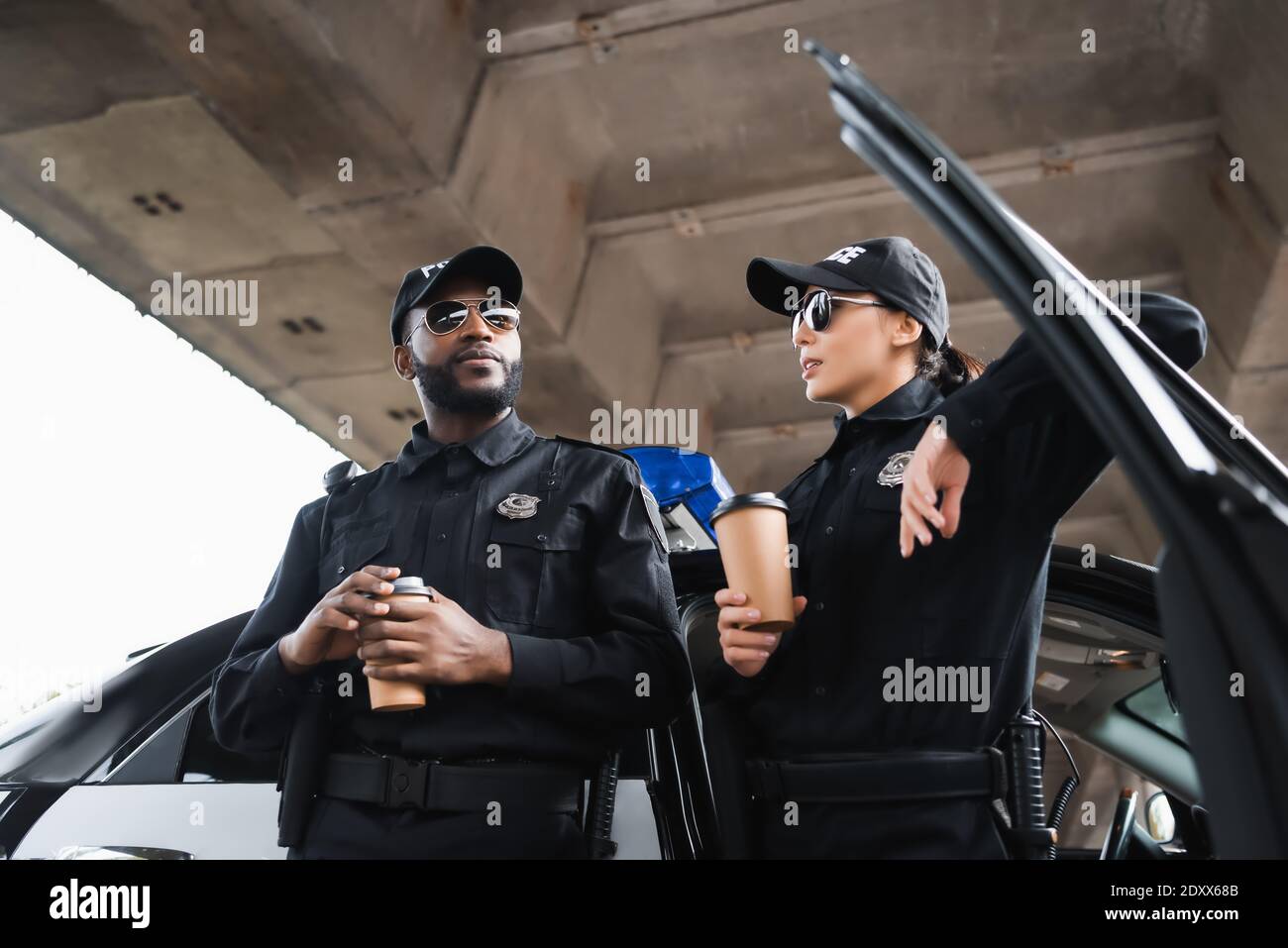 low angle view of multicultural police officers with paper cups leaning ...
