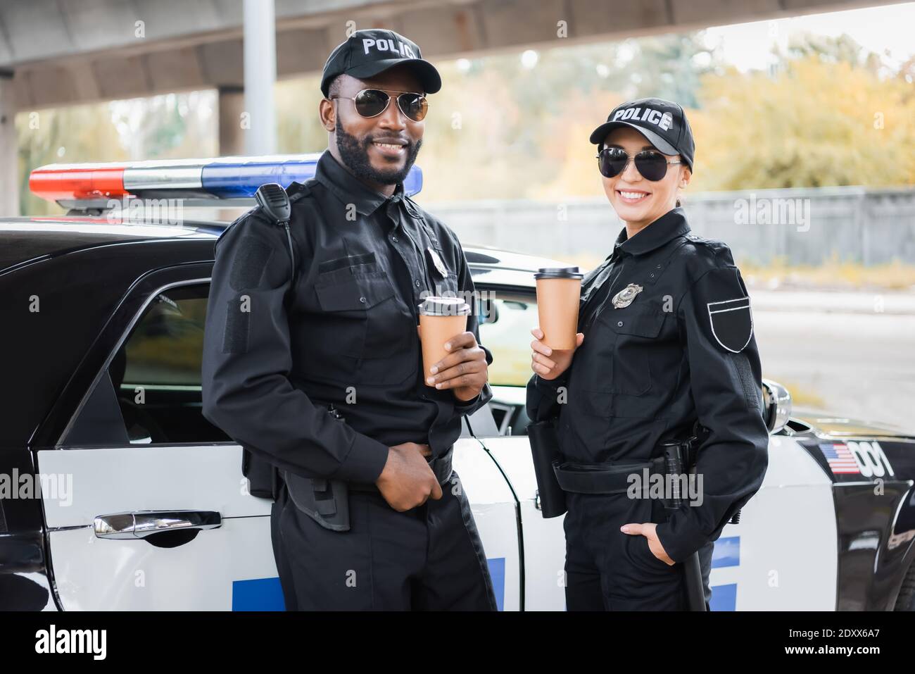 happy multicultural police officers with paper cups looking at camera ...