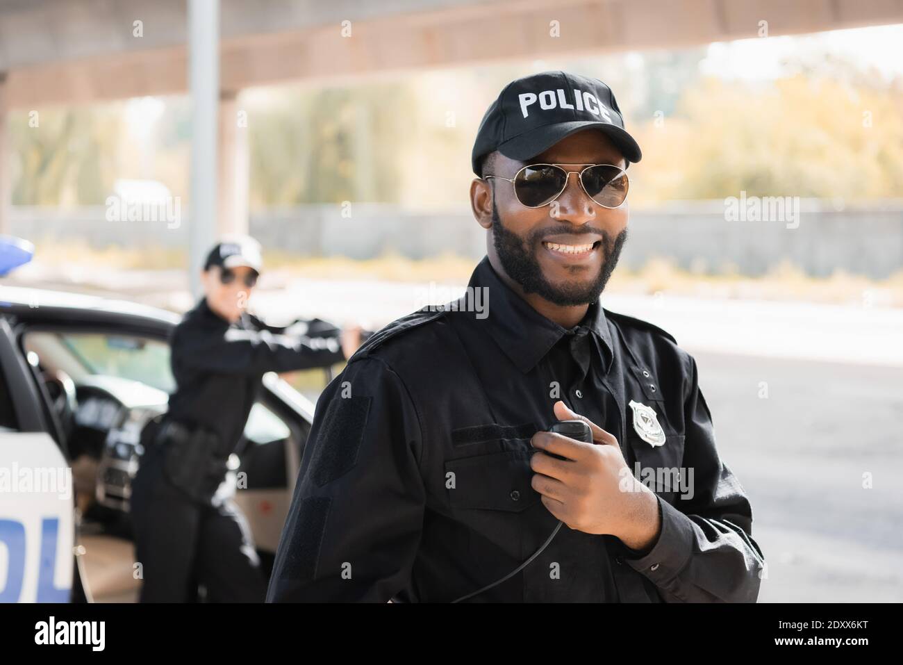 happy african american police officer looking at camera while holding ...