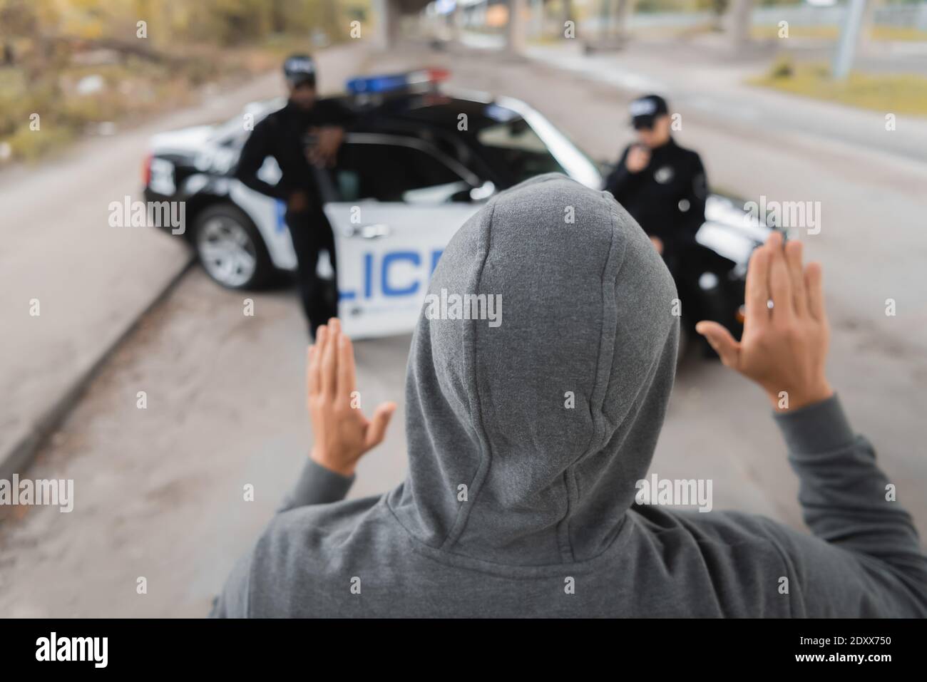 back view of hooded offender showing hands with blurred multicultural ...