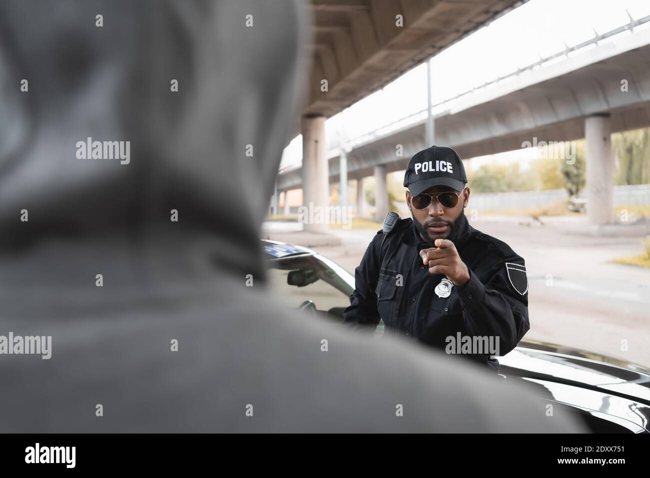 serious african american policeman pointing with finger at blurred ...