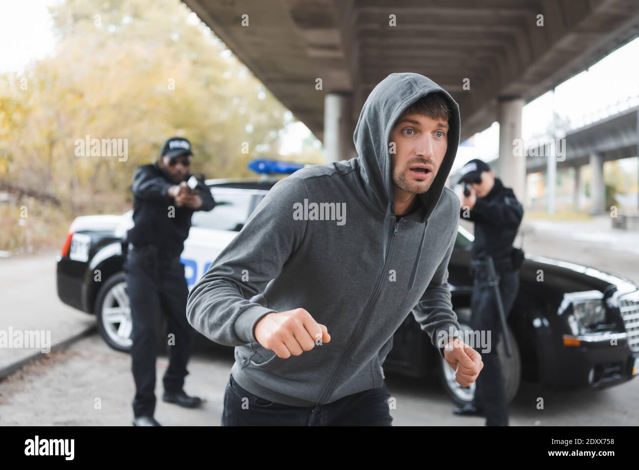 scared hooded offender running from multicultural police officers ...