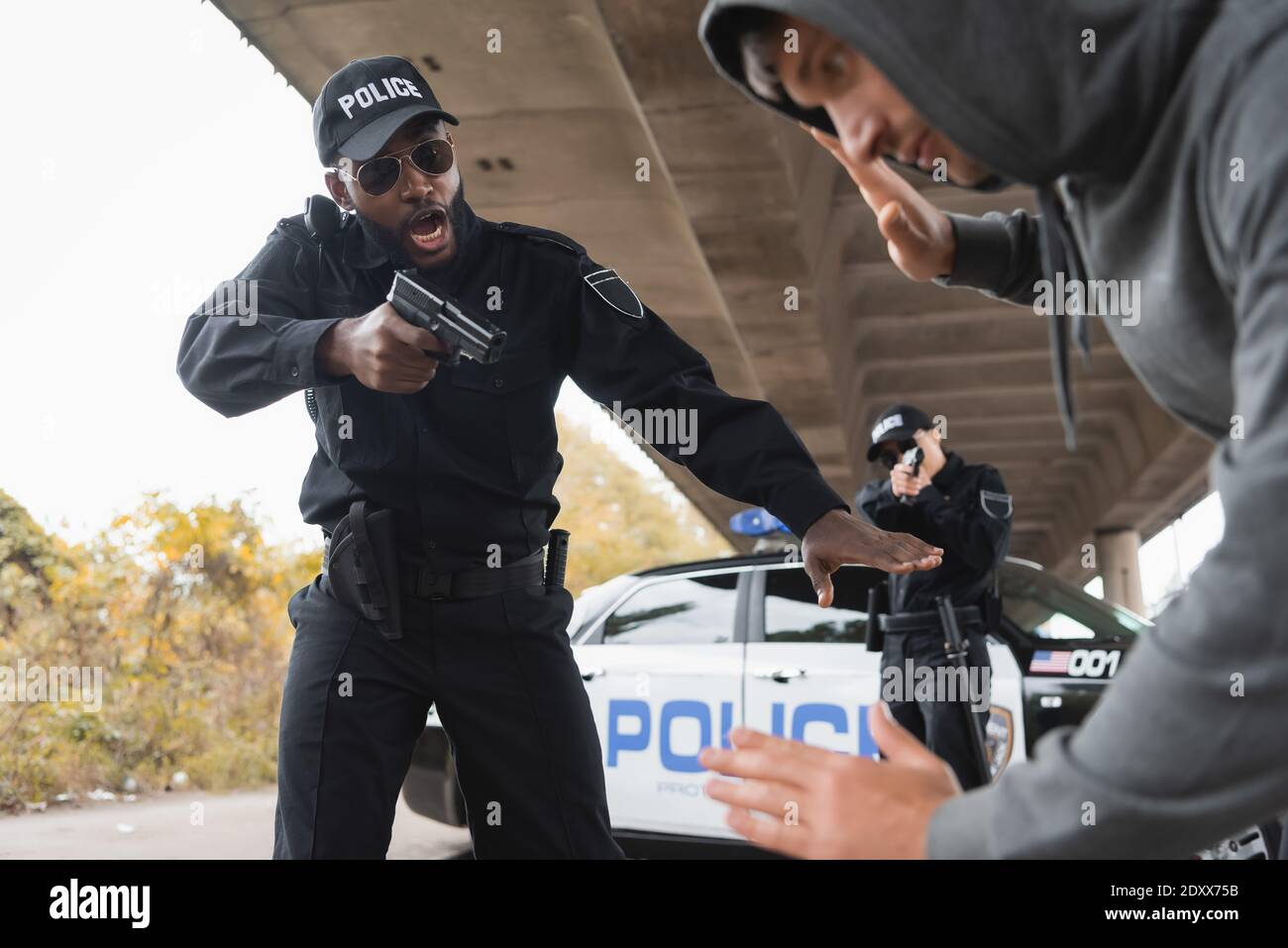 angry african american policeman aiming by pistol at blurred ...