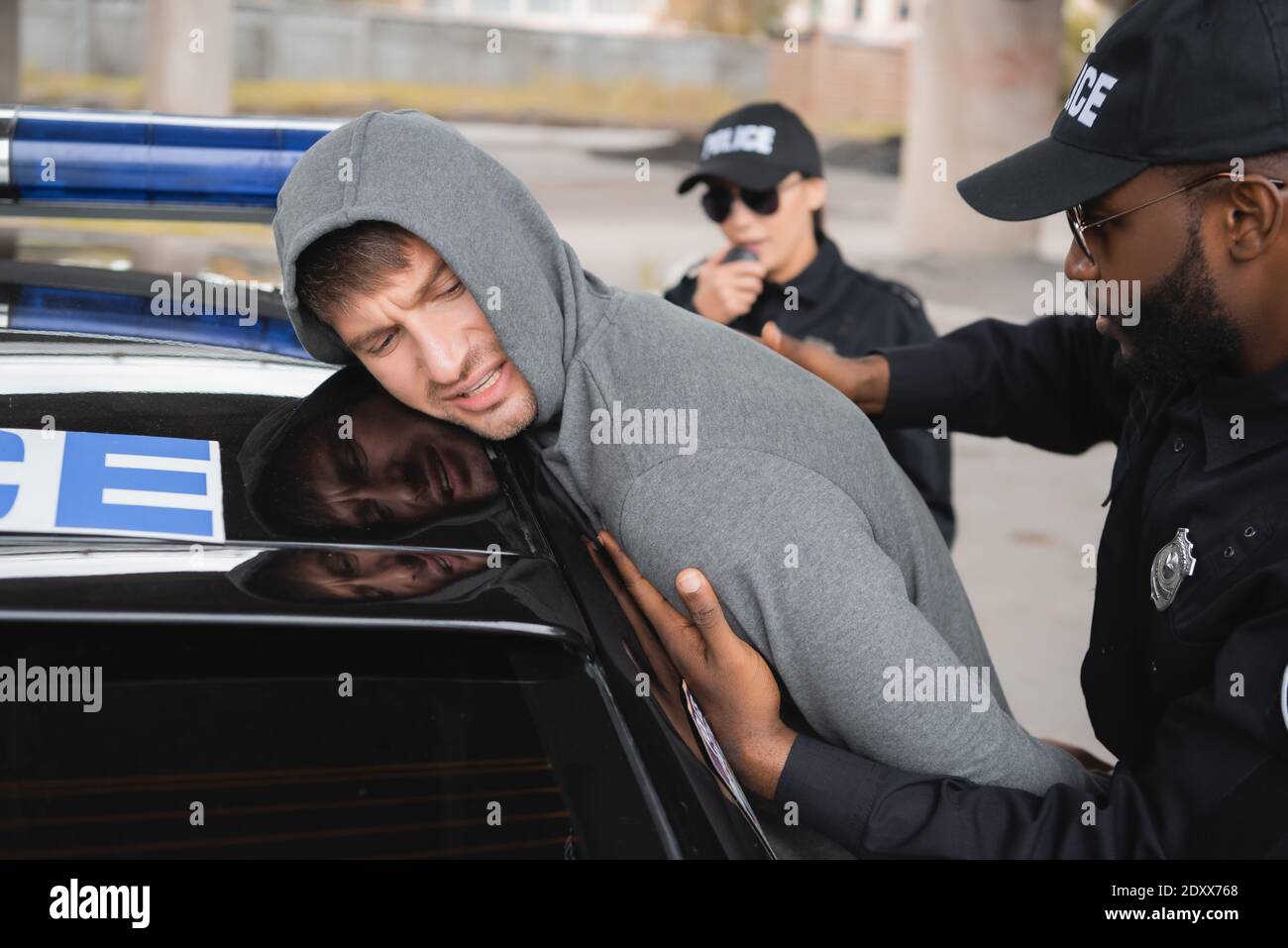 african american policeman frisking angry hooded offender leaning on ...