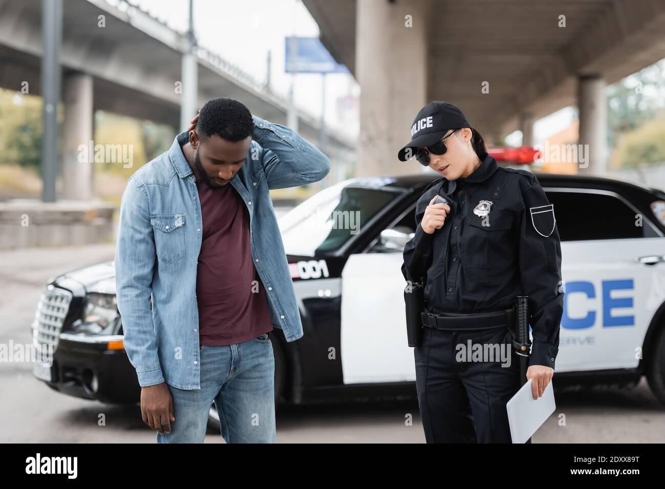 policewoman talking on radio set near african american victim with ...