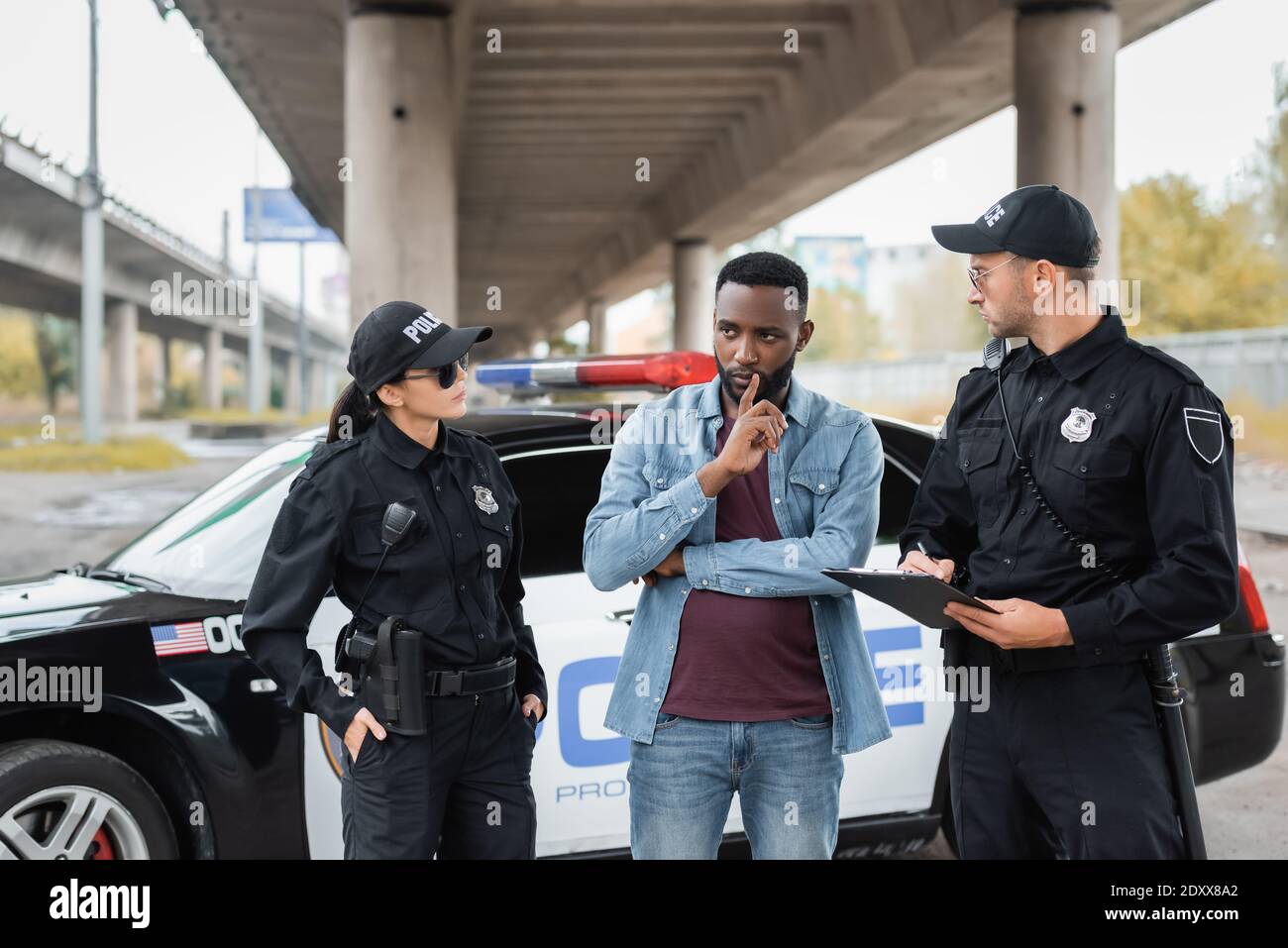 police officers looking at african american victim thinking near patrol ...