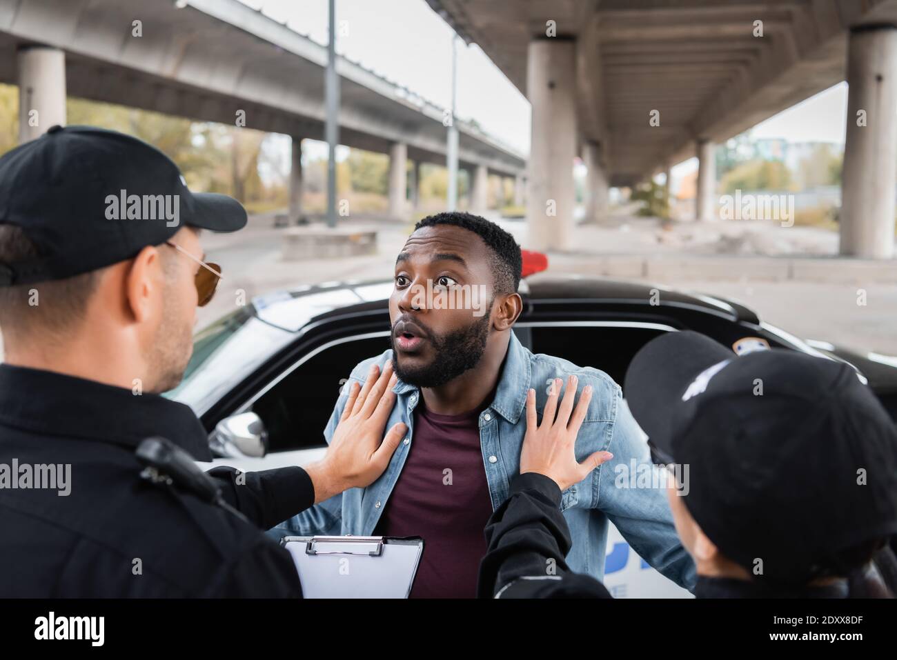 back view of police officers calming shocked african american victim ...