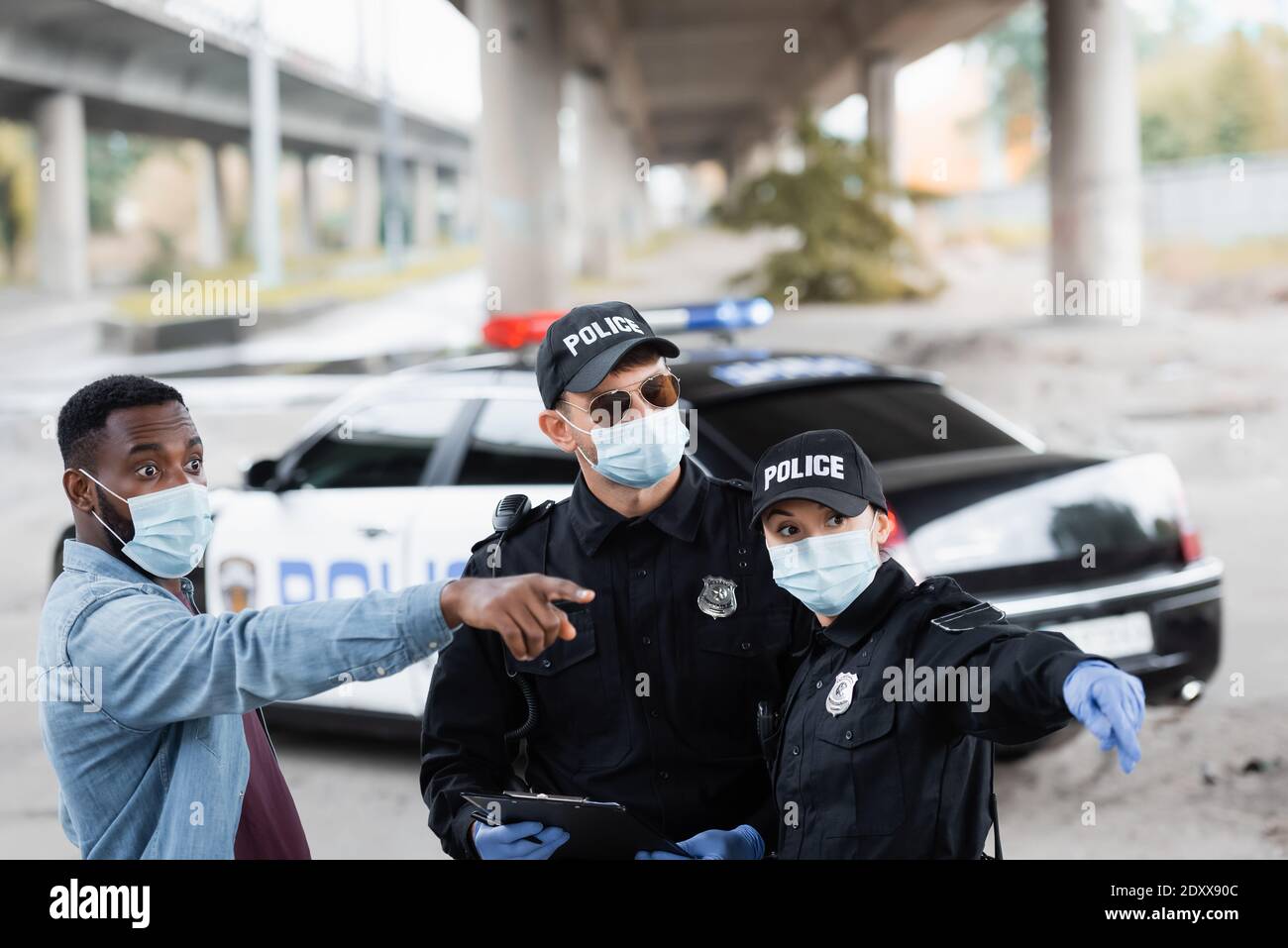 African american victim in medical mask pointing with finger near ...