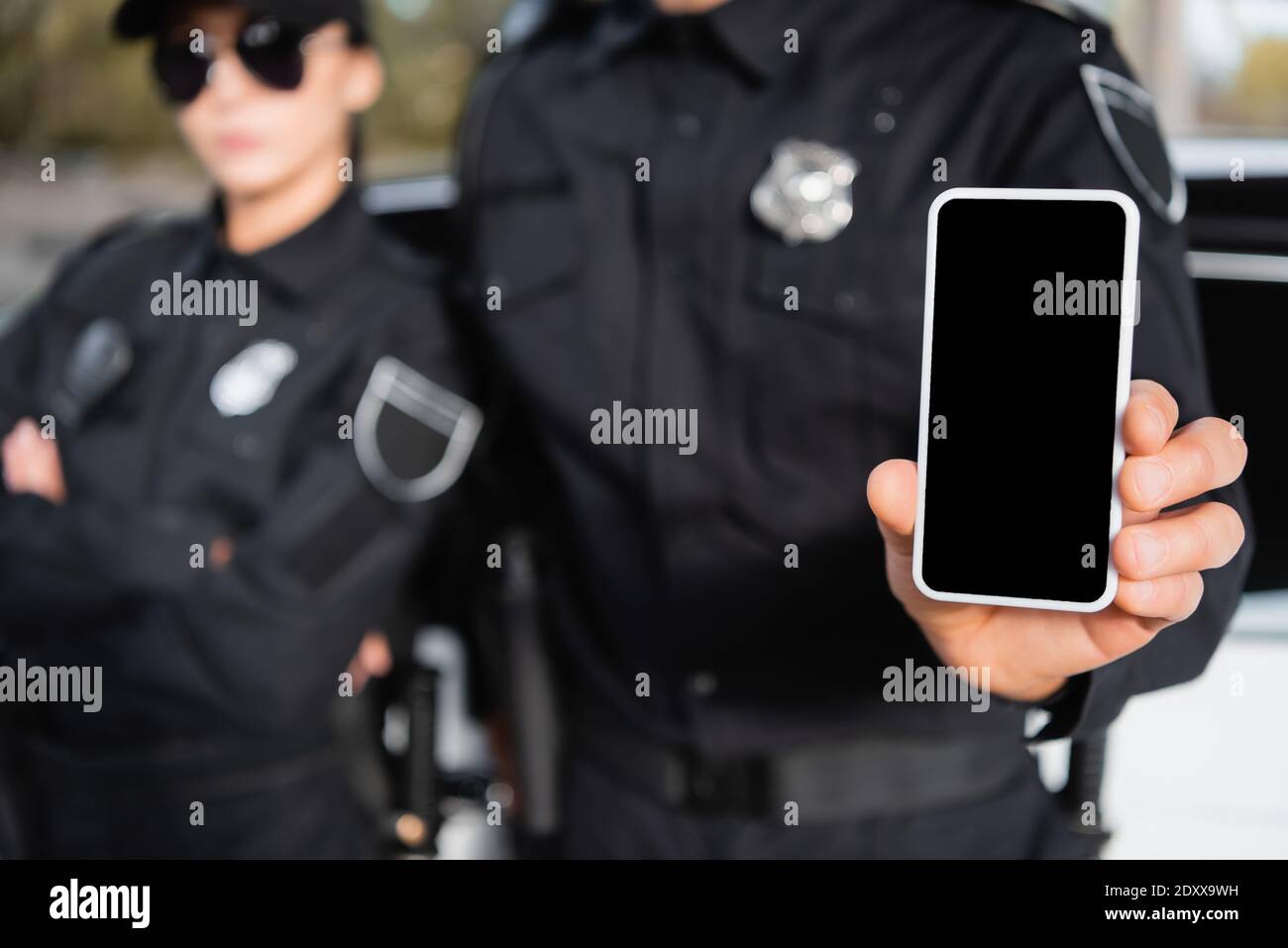 Smartphone with blank screen in hand of police officer near colleague ...