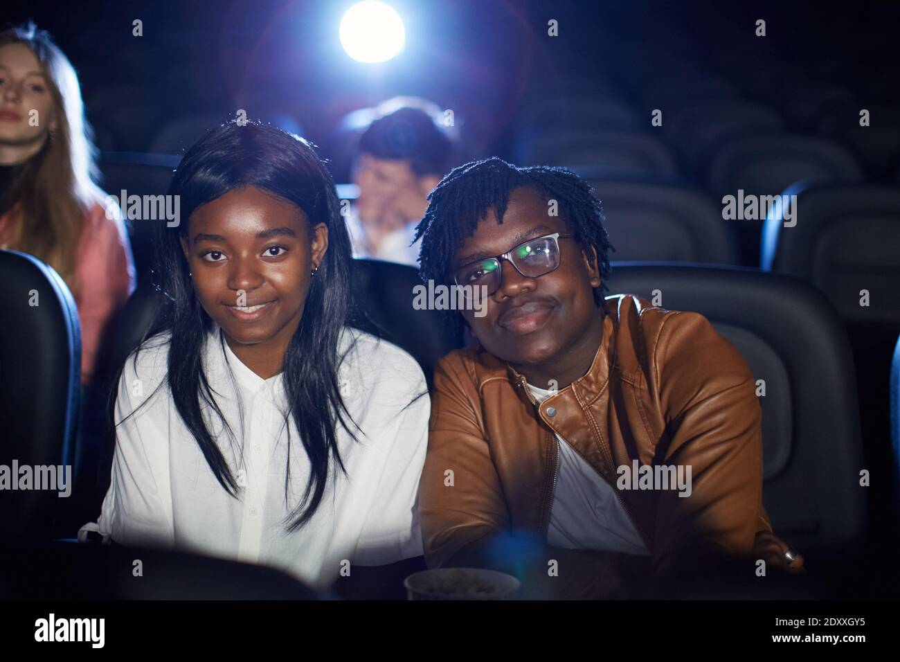 Portrait of young african couple enjoying film in movie theater, posing ...