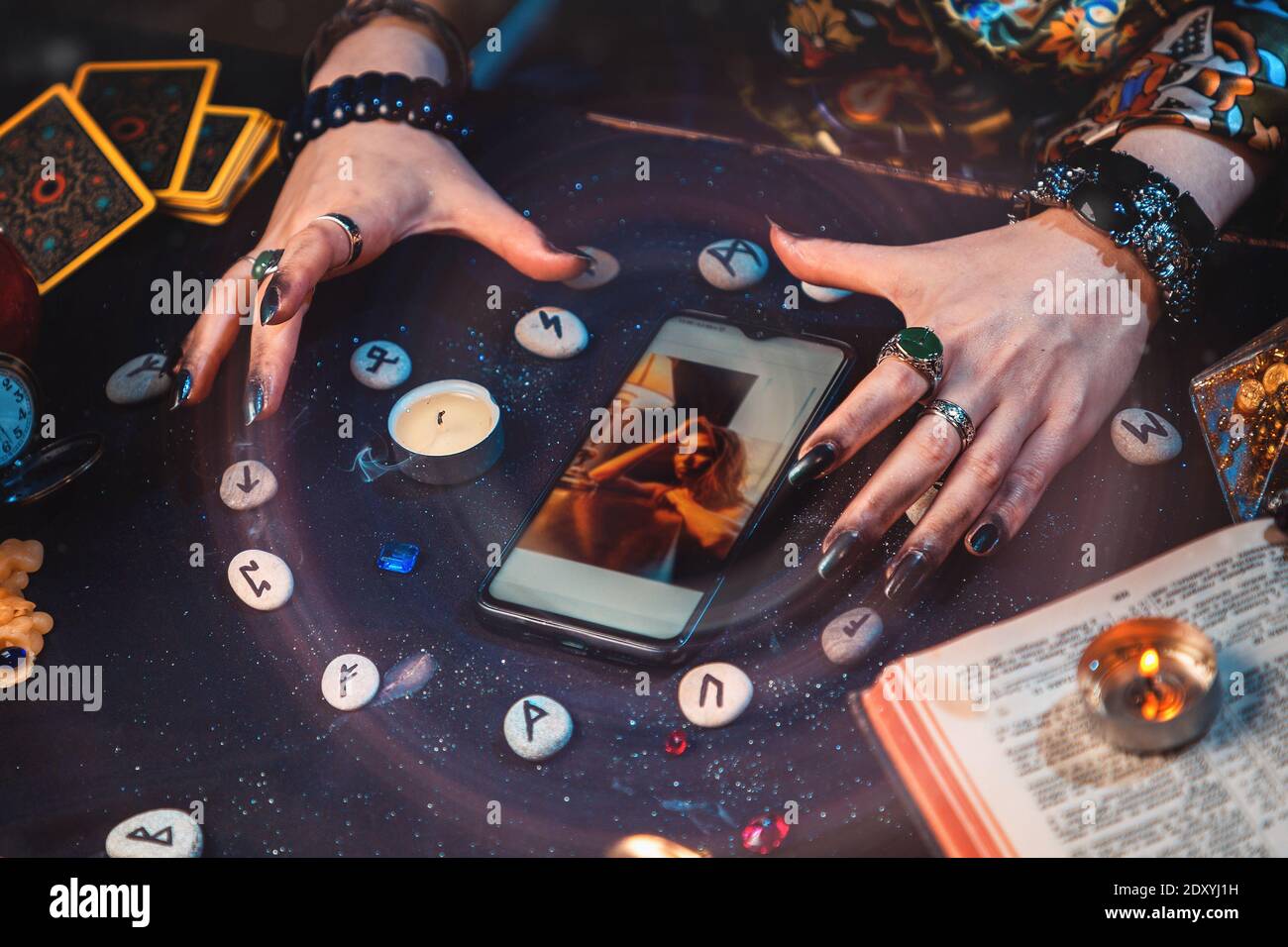 The fortune teller casts a spell on a smartphone with photo. Hands and ...