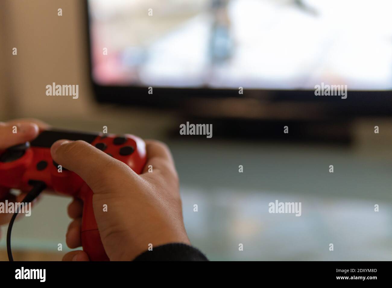 Teenager's hands playing a console with a red remote control with the ...