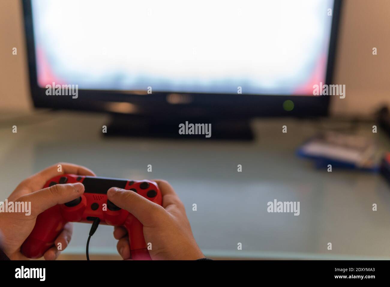 Teenager's hands playing a console with a red remote control with the ...