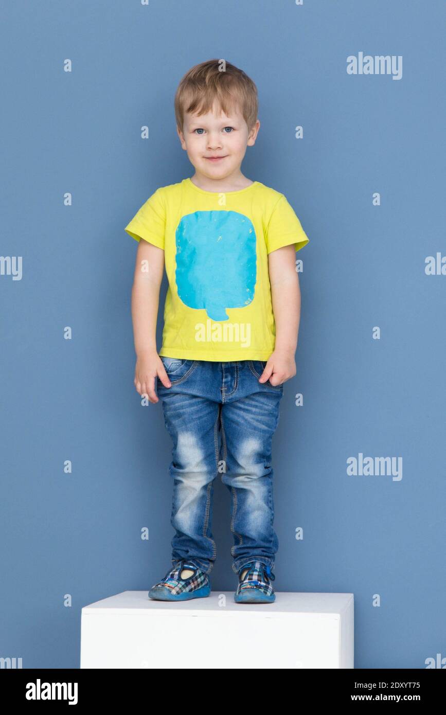 Full Length Of Cute Boy Standing On Block Against Wall At Home Stock ...