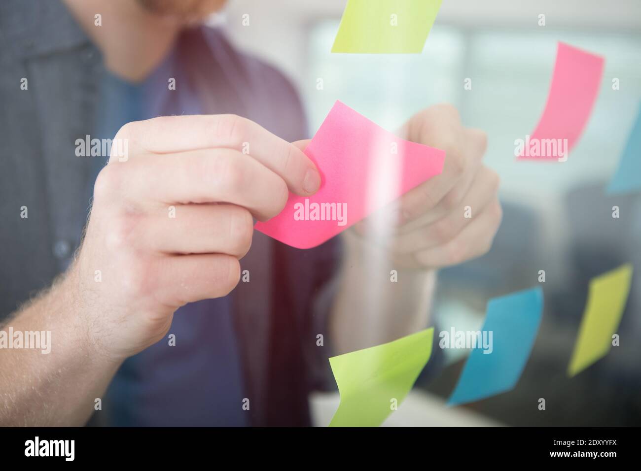 male office worker with hand on sticky note on window Stock Photo - Alamy