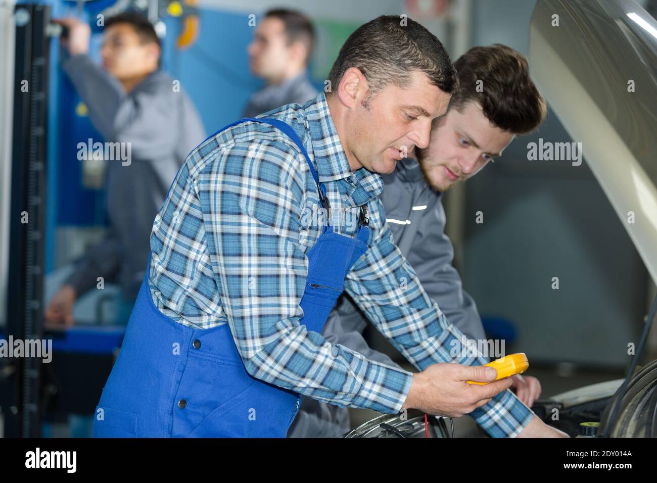 mechanic inspecting the battery of the vehicle Stock Photo - Alamy