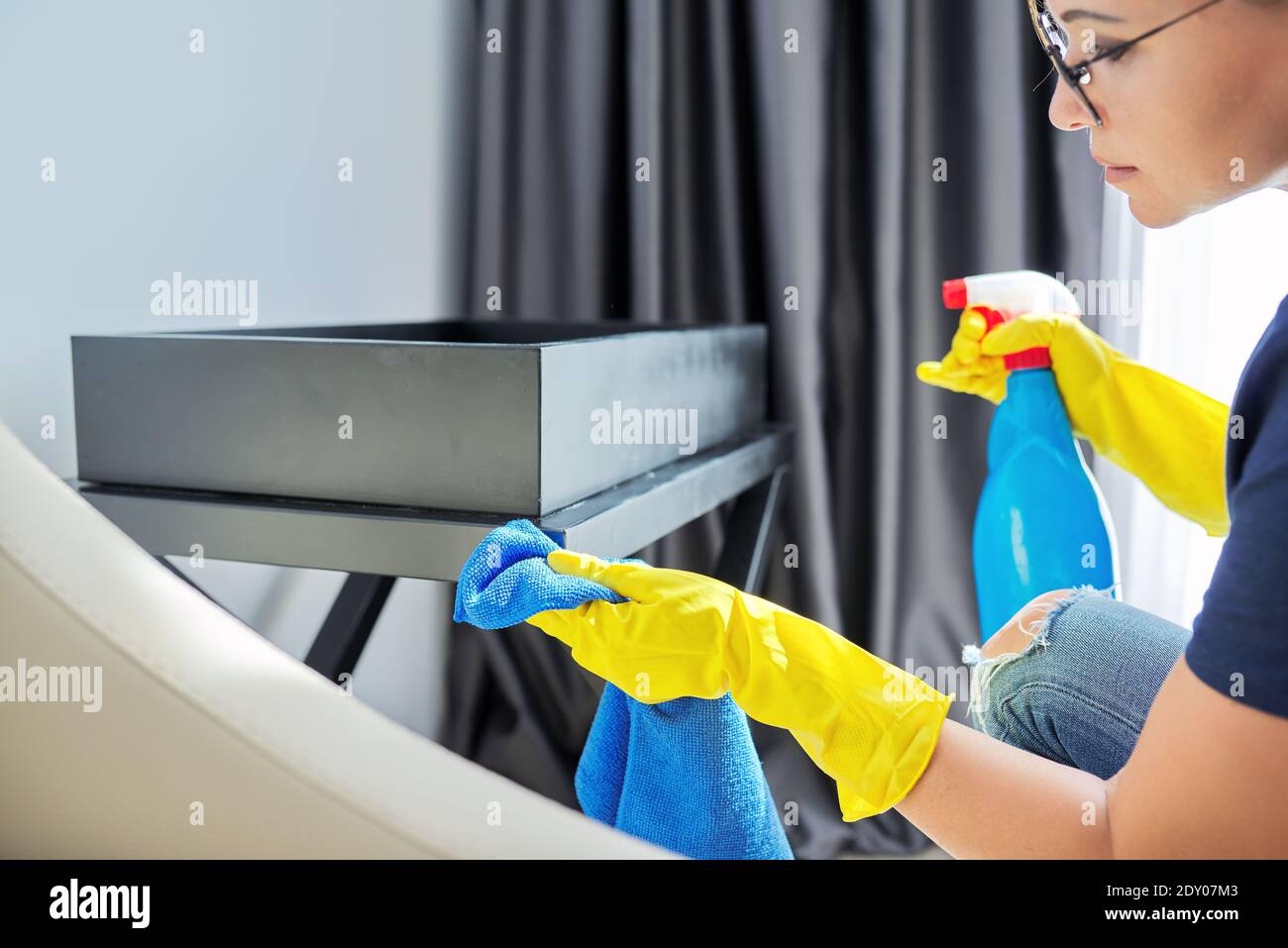 House cleaning, woman in gloves with a rag and spray wiping dust and ...