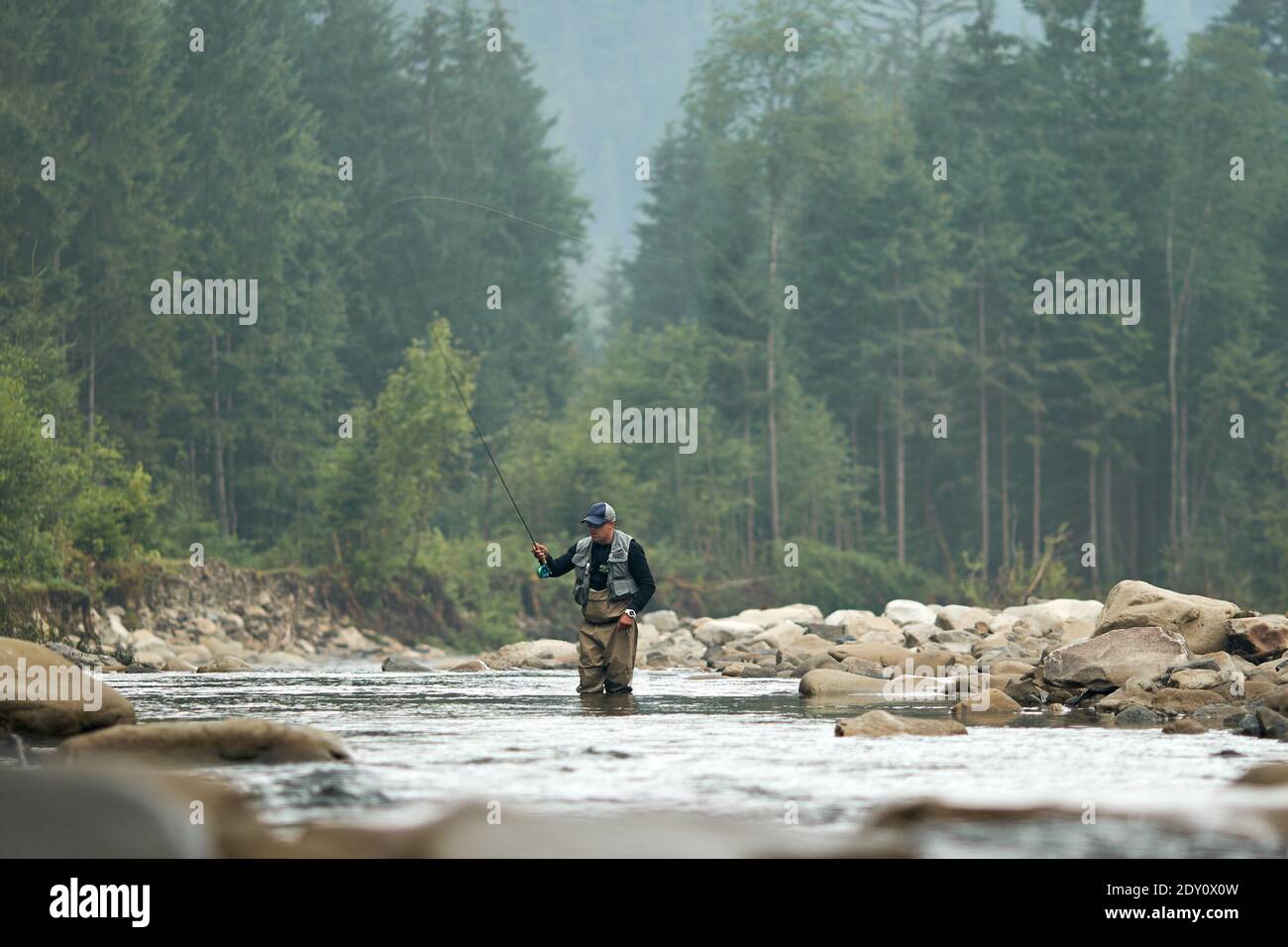 Fisherman in special clothing and boots using professional rod for ...