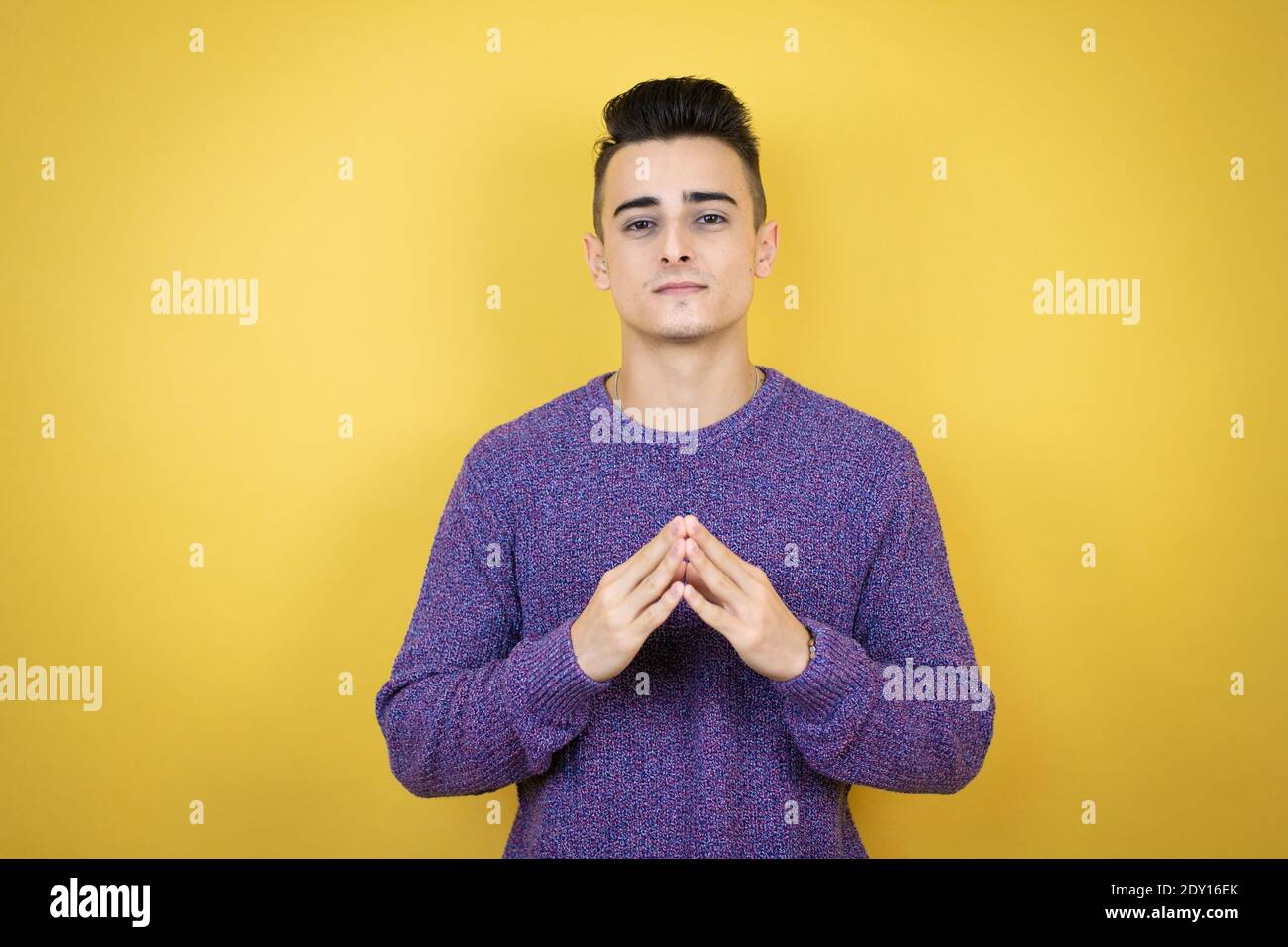 Young caucasian man over isolated yellow background with Hands together ...