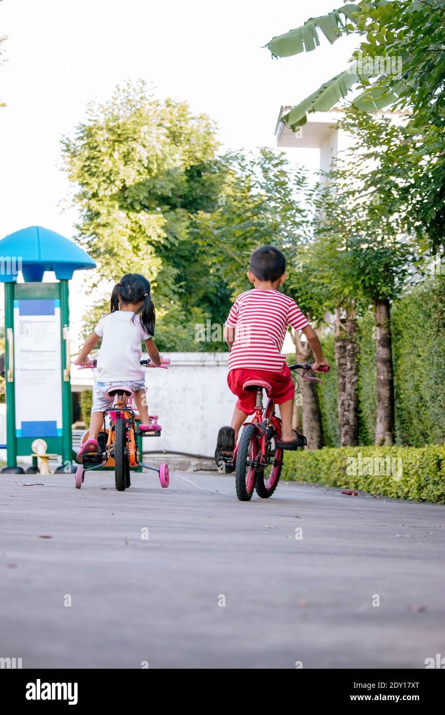 Rear View Of Kids Riding Bicycle On Road Stock Photo - Alamy
