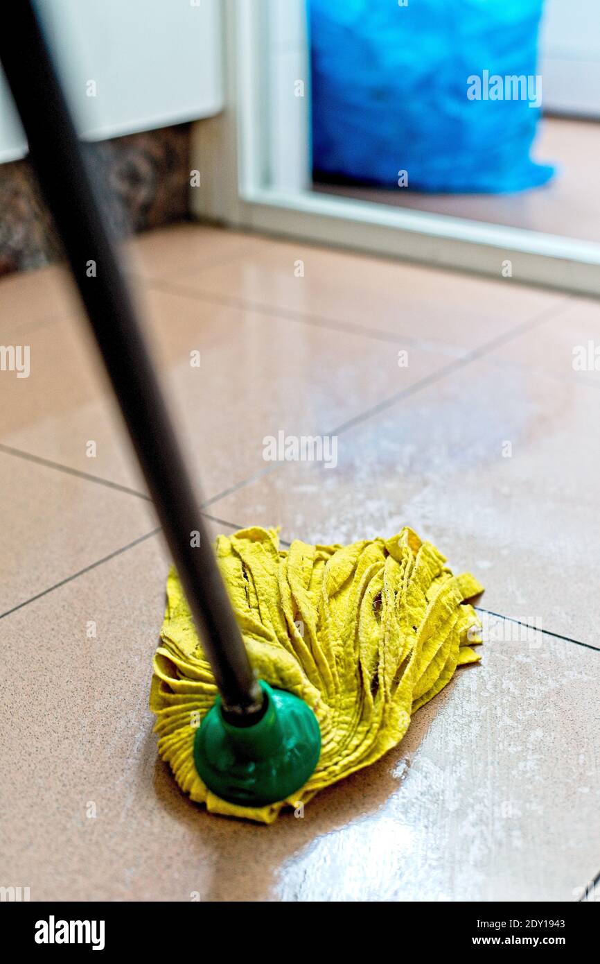 A vertical shot of a yellow dirty mop on the floor under the lights ...