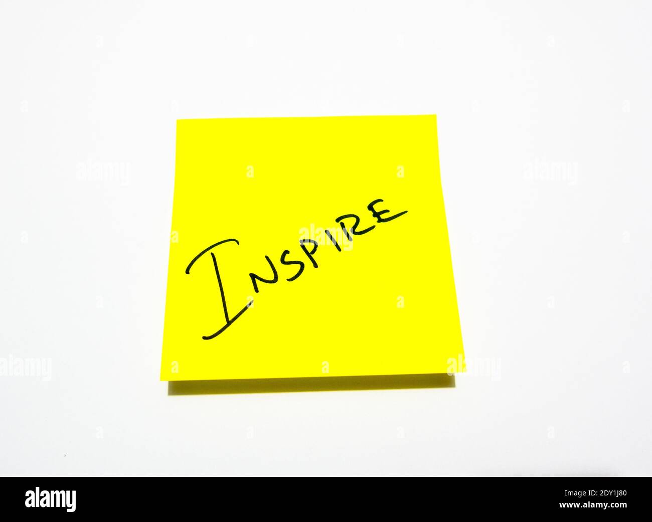Inspire hand written note on a yellow sticky note with white background ...