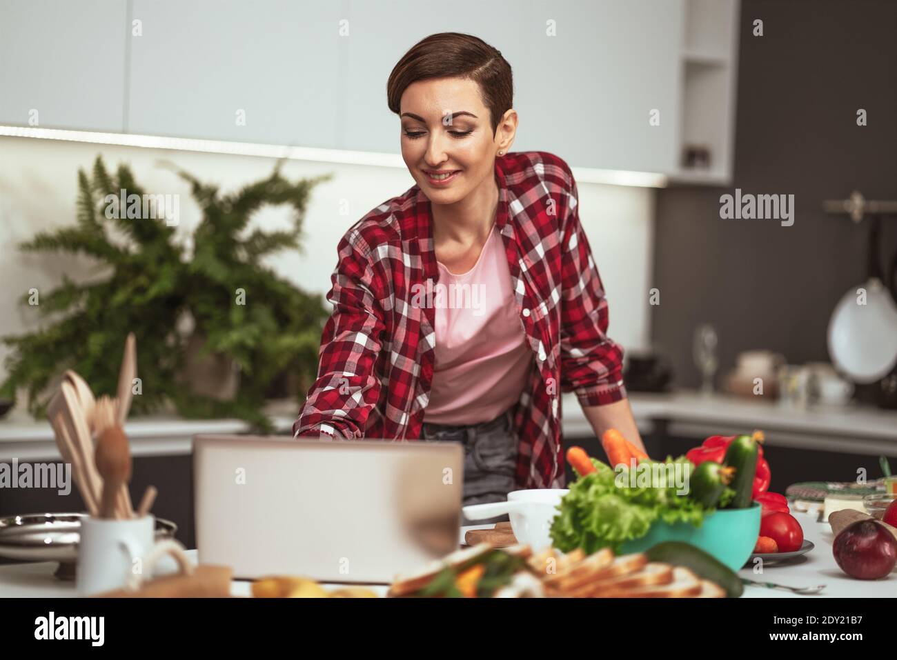 Making a video call using laptop computer housewife while cooking or ...