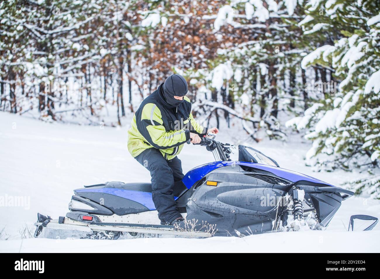 Man is riding snowmobile in mountains. Pilot on a sports snowmobile in ...