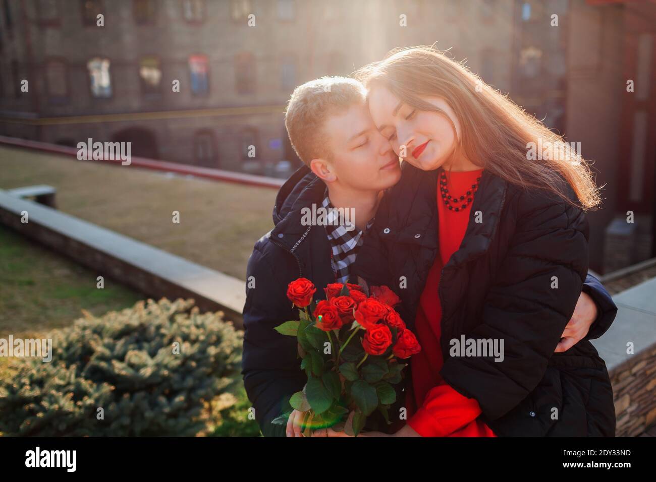 Valentine's day date. Man hugging girlfriend holding bouquet of red ...