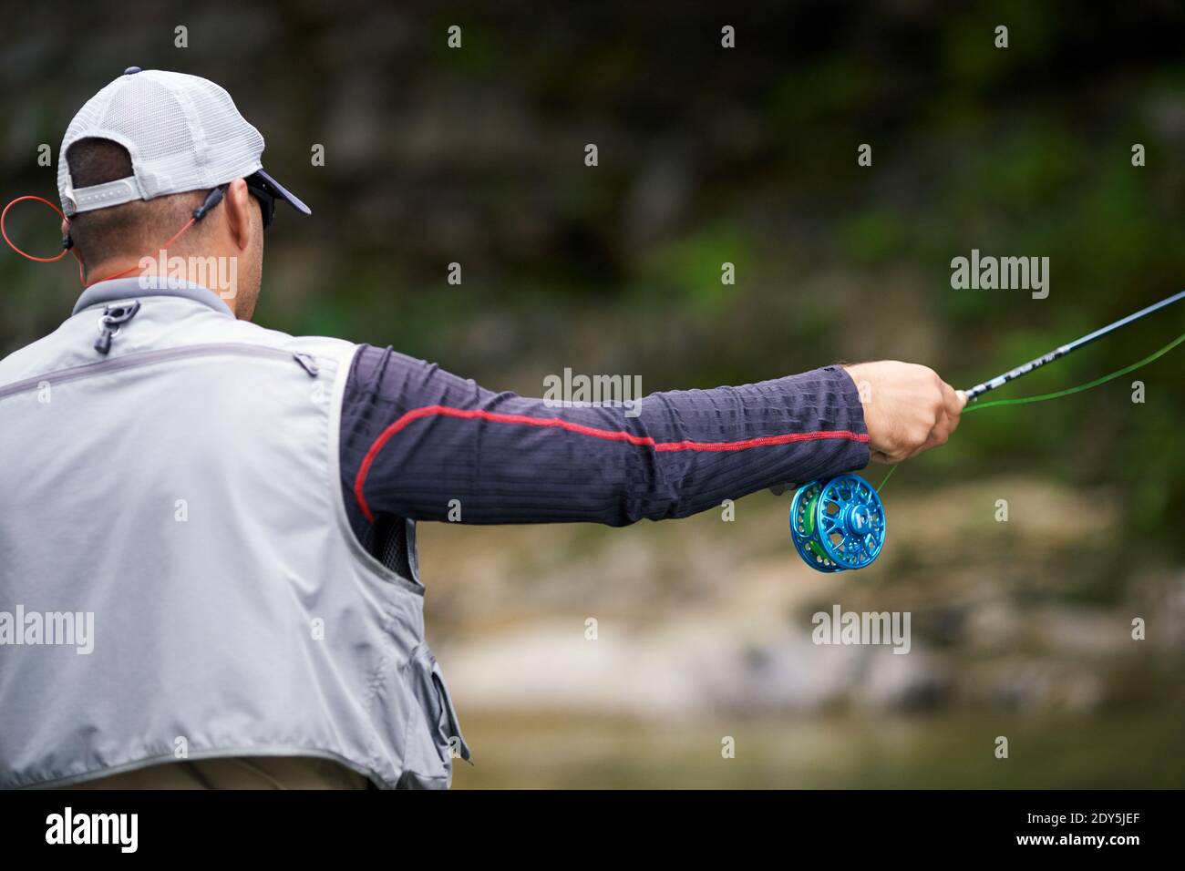 Back view of professional fisherman in special uniform using spinning ...