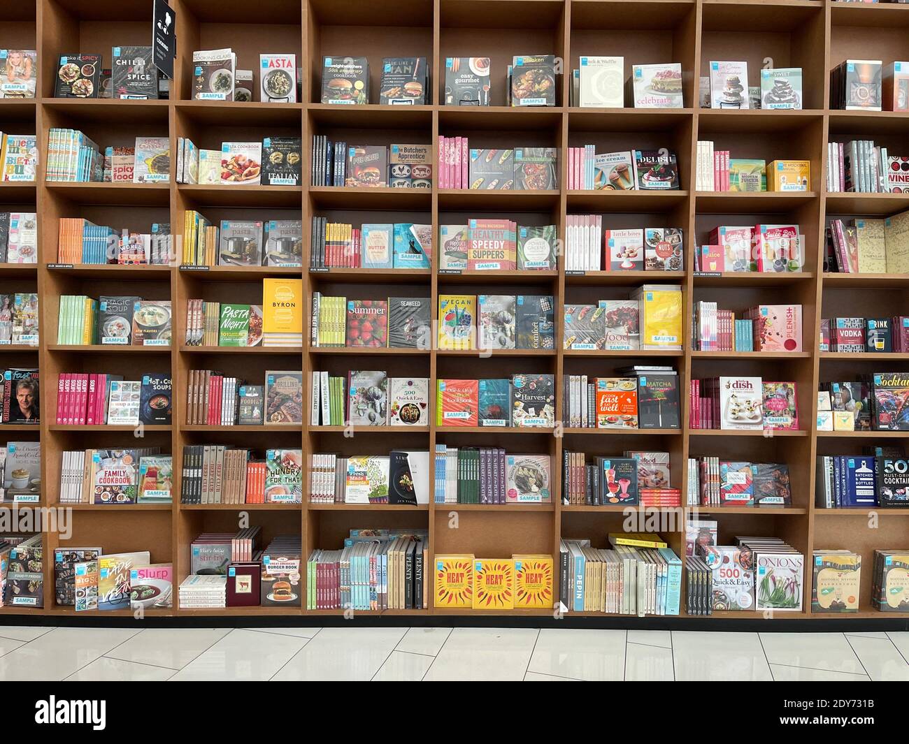 Rows of different colorful books lying on the shelves in the modern ...