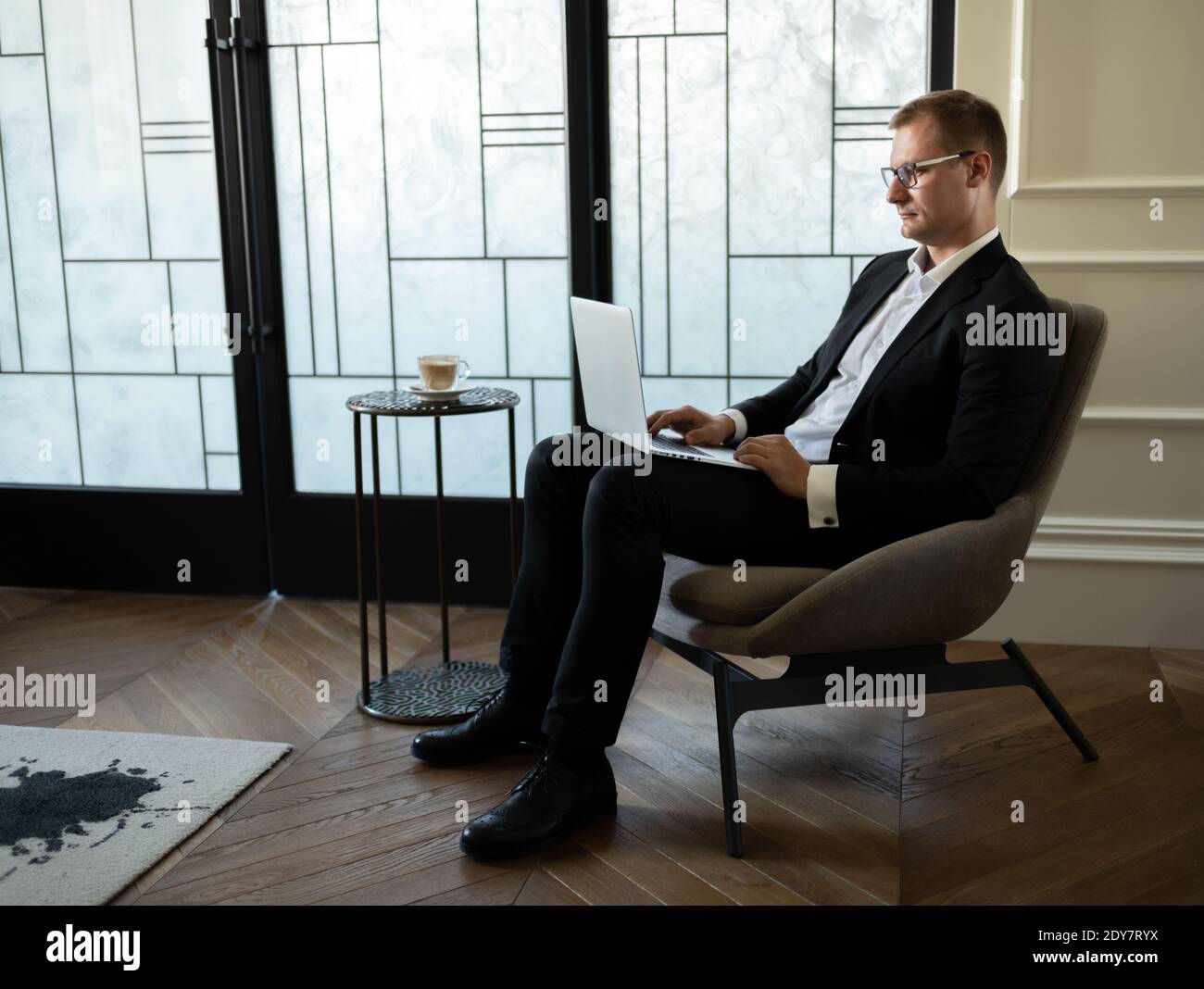 Side view of adult male employee in formal suit sitting in comfy chair ...