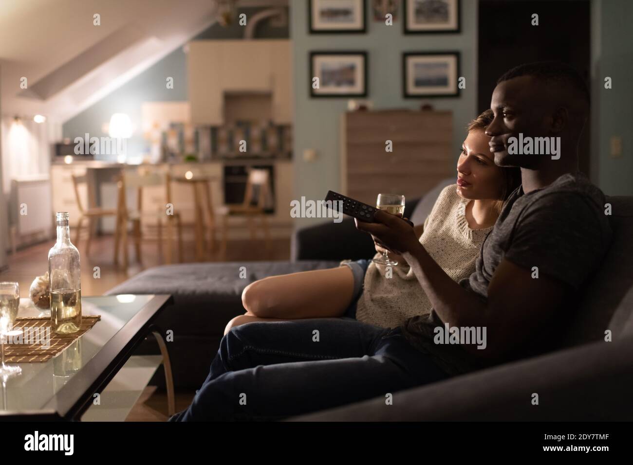 Side view of diverse man with remote control and woman with wine ...