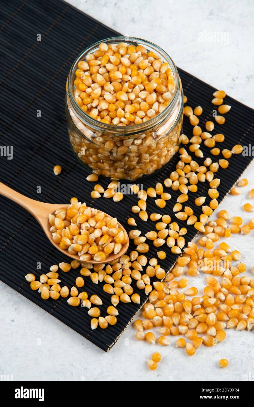Glass jar of corn kernels with spoon on black cutting board Stock Photo ...