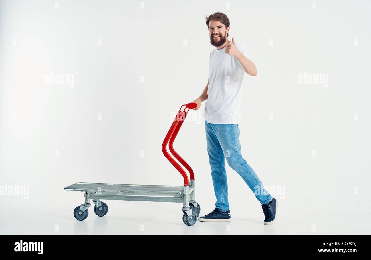 cargo trolley man in jeans and sneakers light background work ...