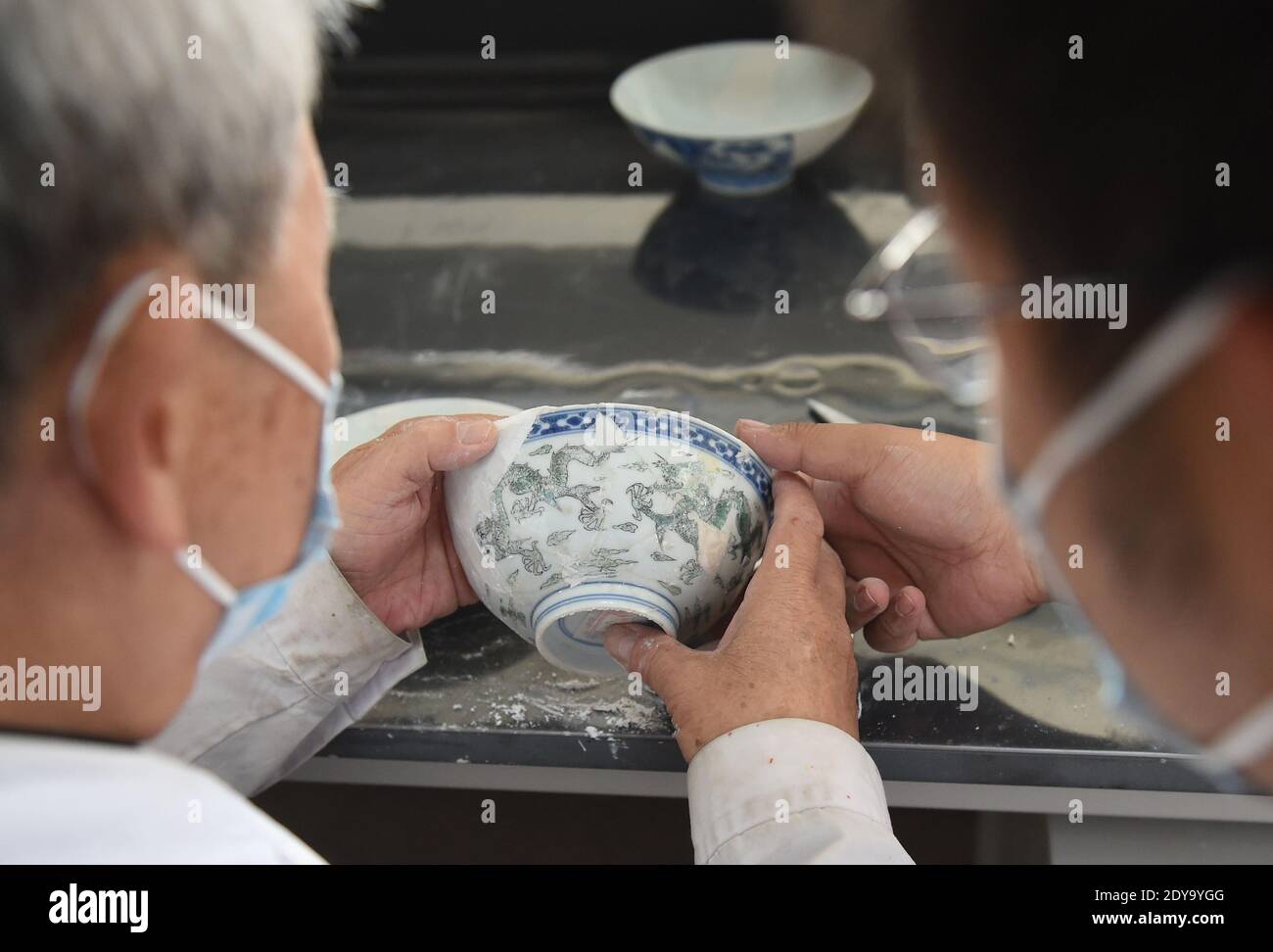 Beijing, China. 24th Dec, 2020. Staff members repair a broken porcelain ...