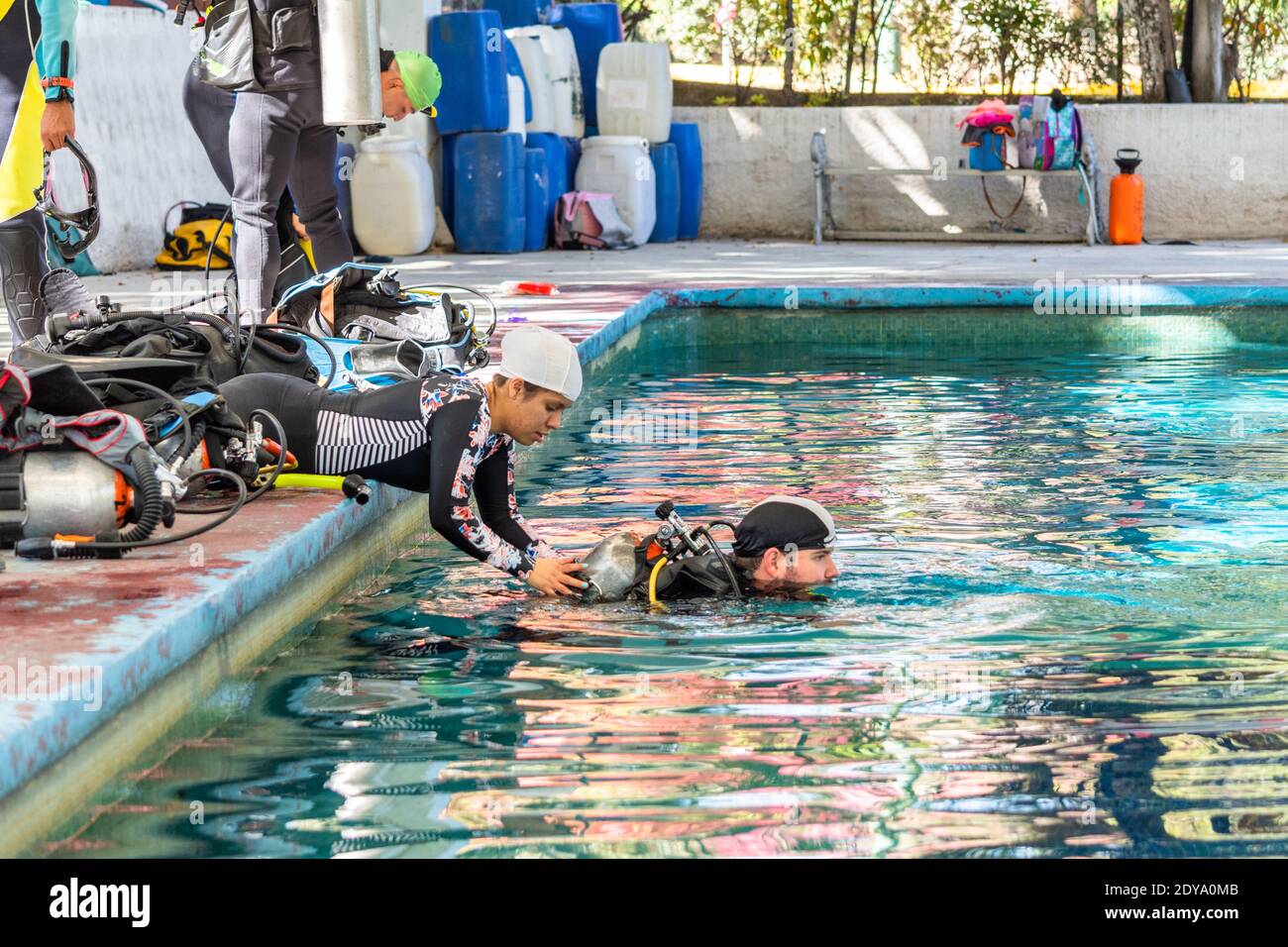 scuba instructor helping a trainee with the oxygen tank while in the ...