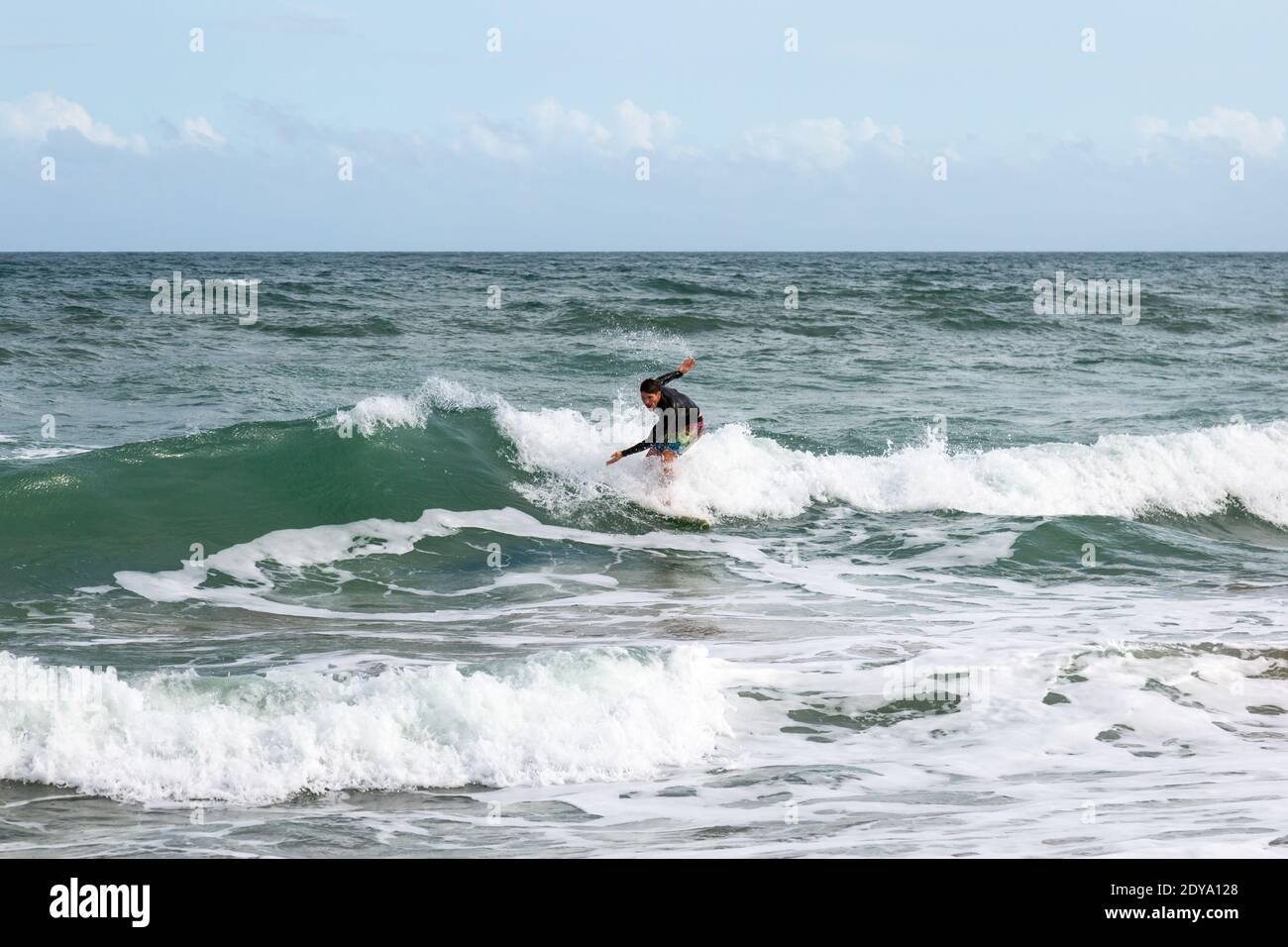 A surfer rides a wave along Hutchinson Island in Stuart, Florida, USA ...