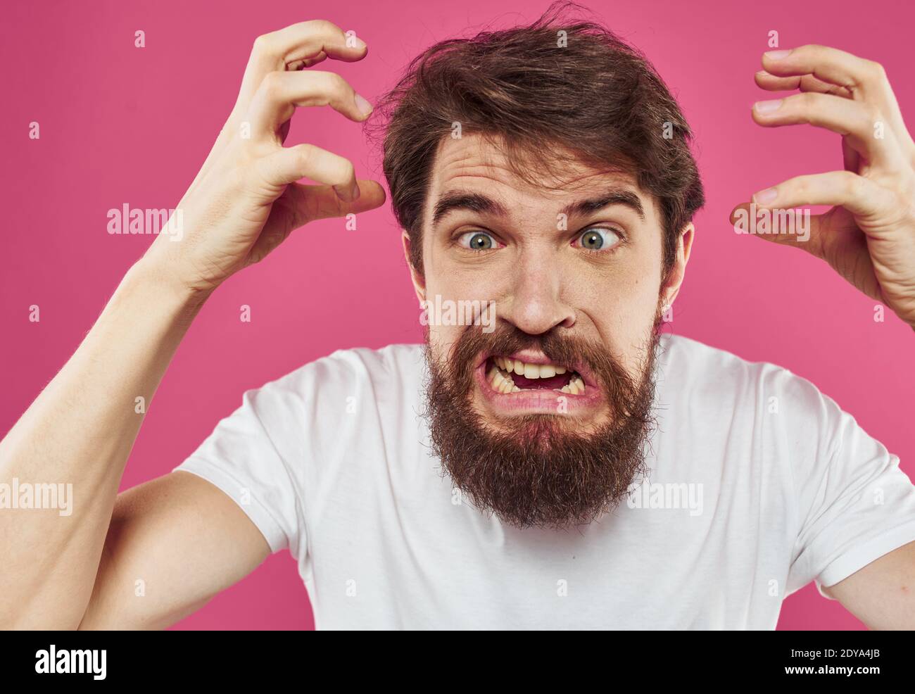 Man holds his hands near his face on a pink background stress ...