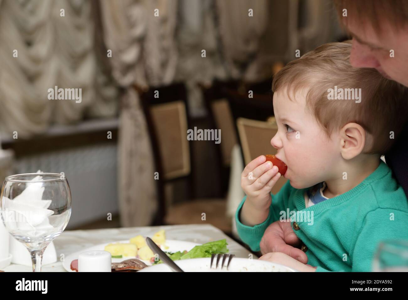 Boy is eating tomato in a restaurant Stock Photo - Alamy