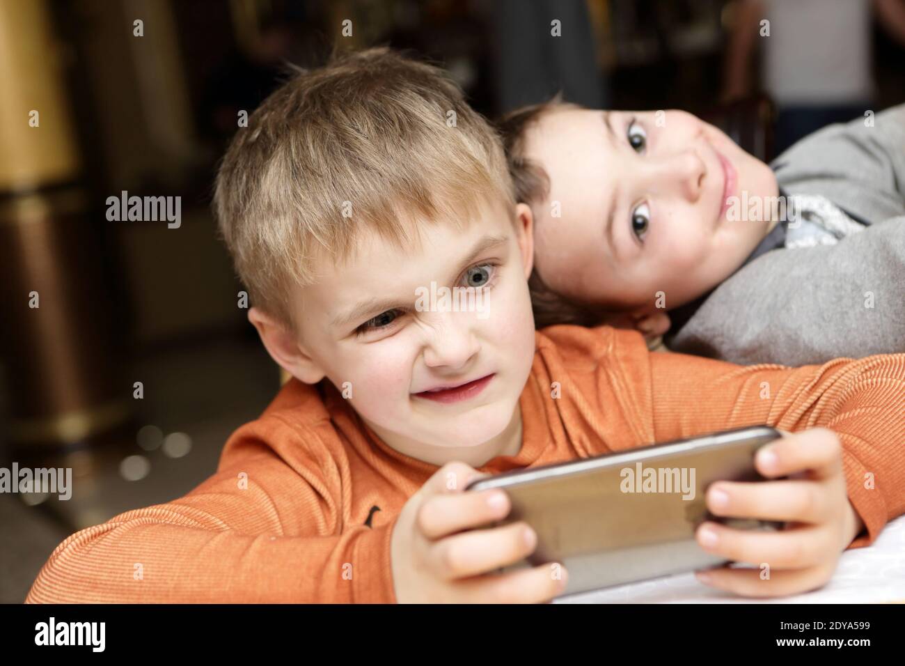 Two children playing in smartphone in cafe Stock Photo - Alamy