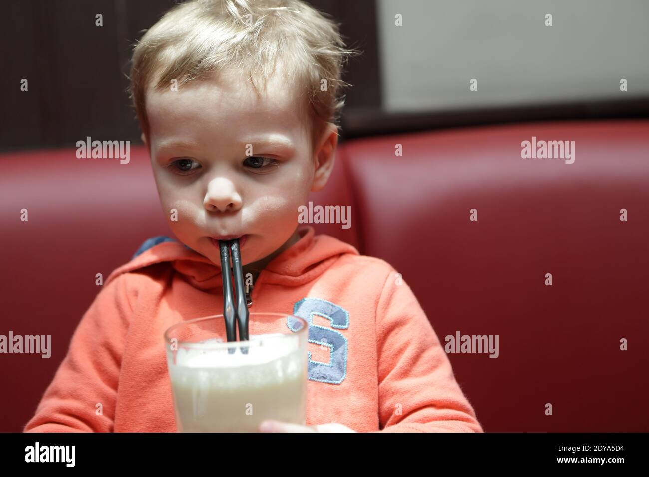 Boy drinking milkshake on sofa in cafe Stock Photo - Alamy